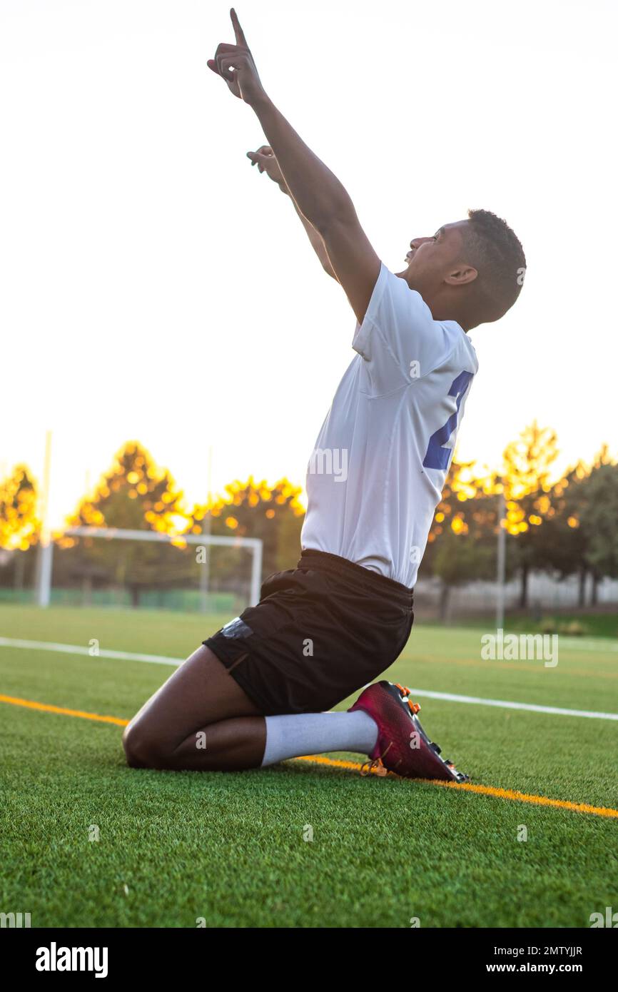 A vertical shot of a Hispanic male soccer player on his knees ...
