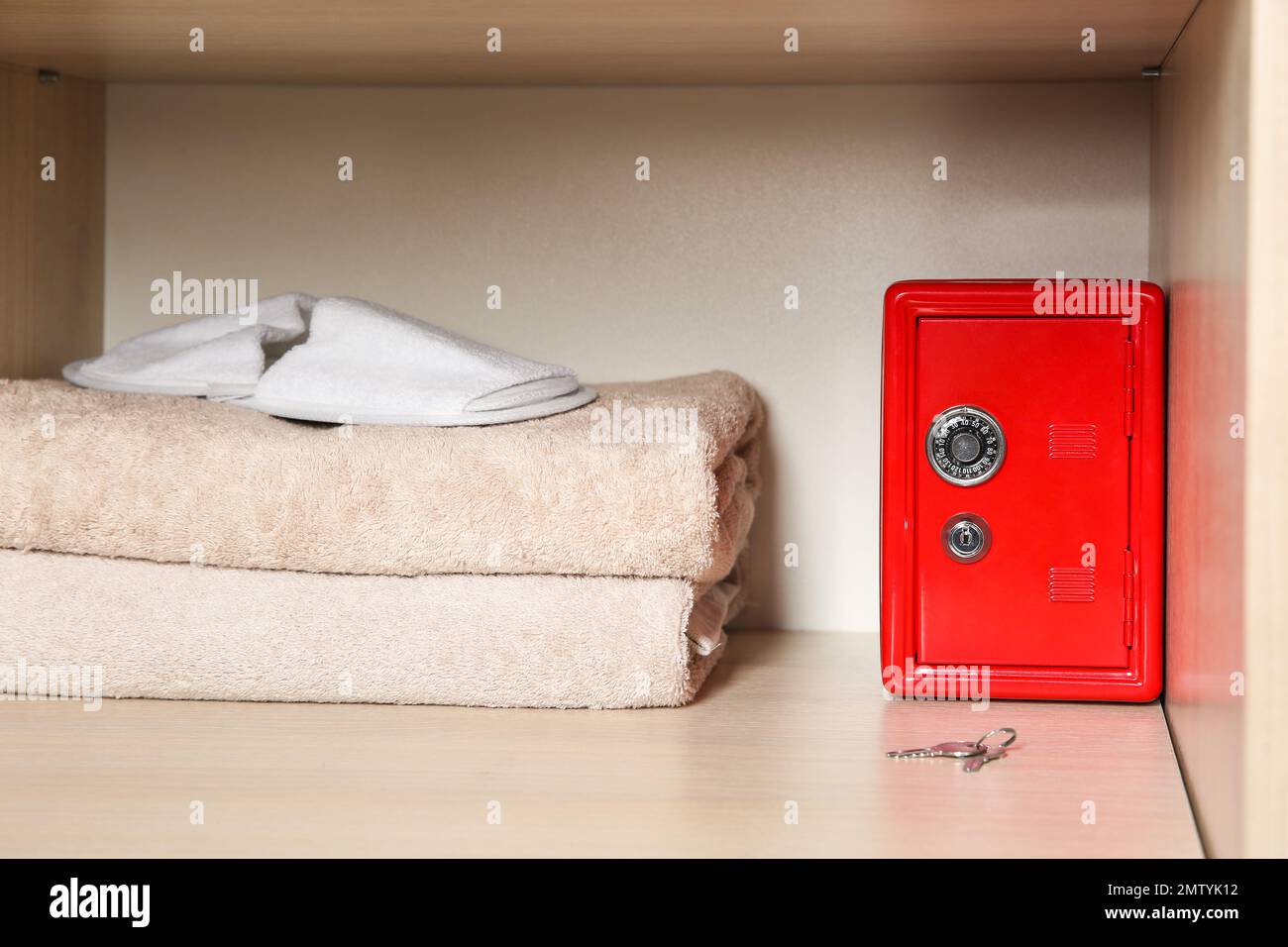 Red steel safe with mechanical combination lock on wooden shelf at ...