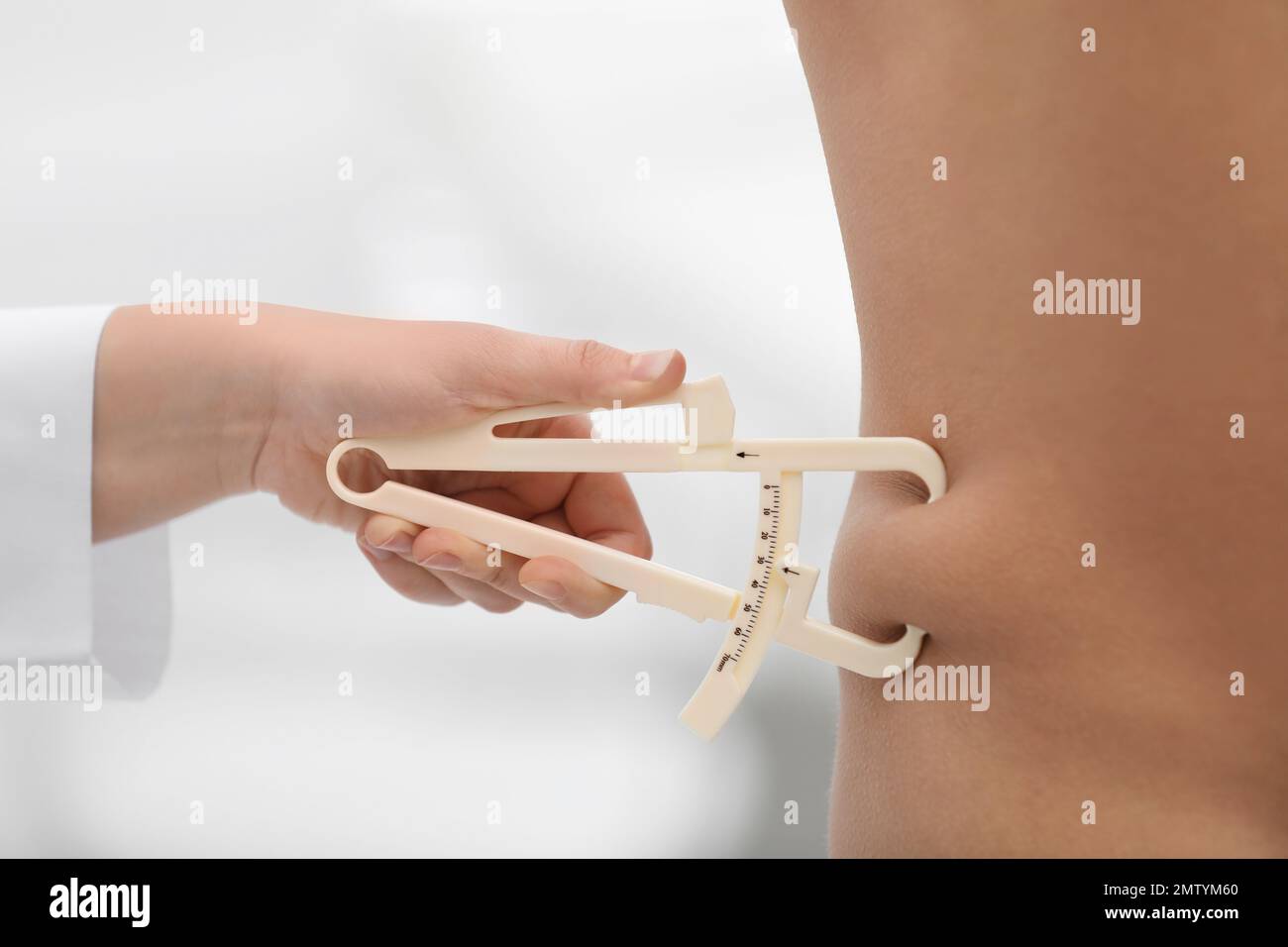 Nutritionist measuring man's body fat layer with caliper on blurred ...