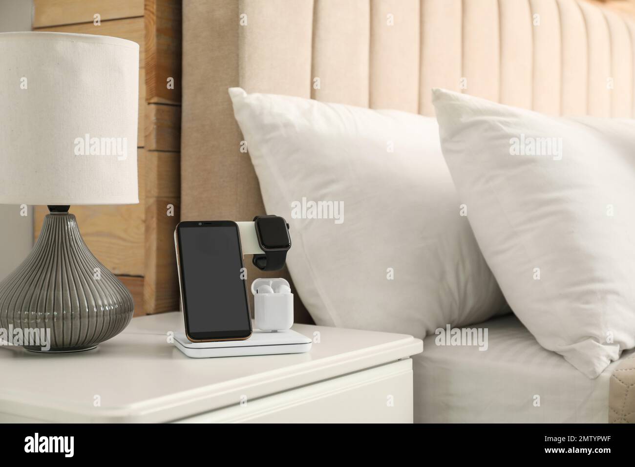 Different gadgets charging on wireless pad in bedroom Stock Photo - Alamy