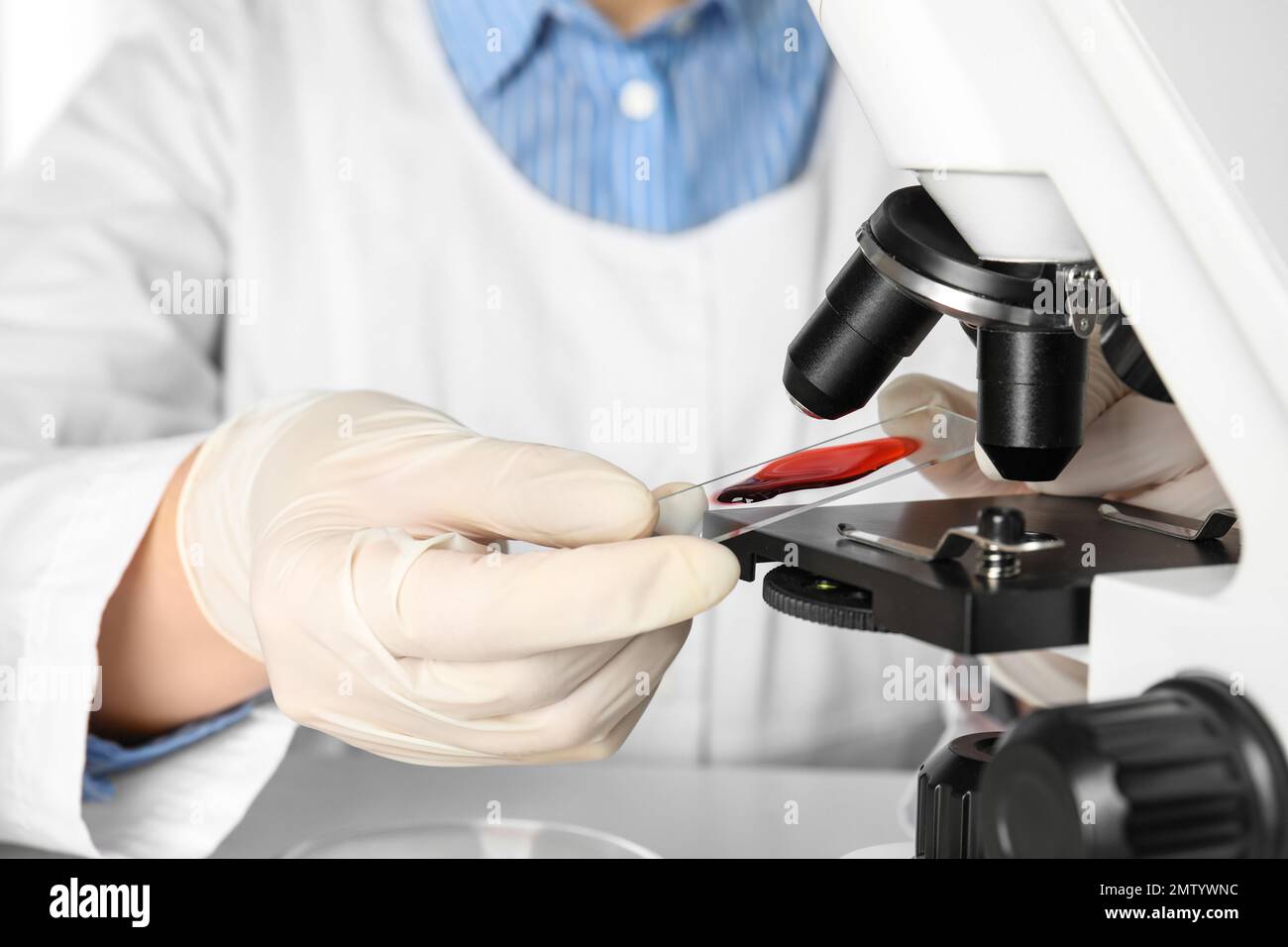 Scientist holding slide with blood sample near microscope in laboratory ...