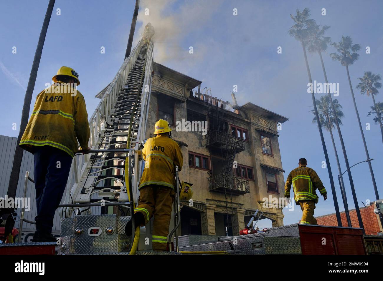 Los Angeles fire department firefighters look on as the last embers of ...
