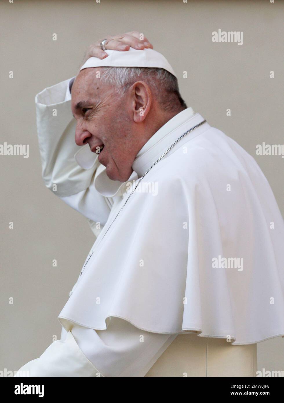 Pope Francis holds his skull cap as he arrives for his weekly general ...