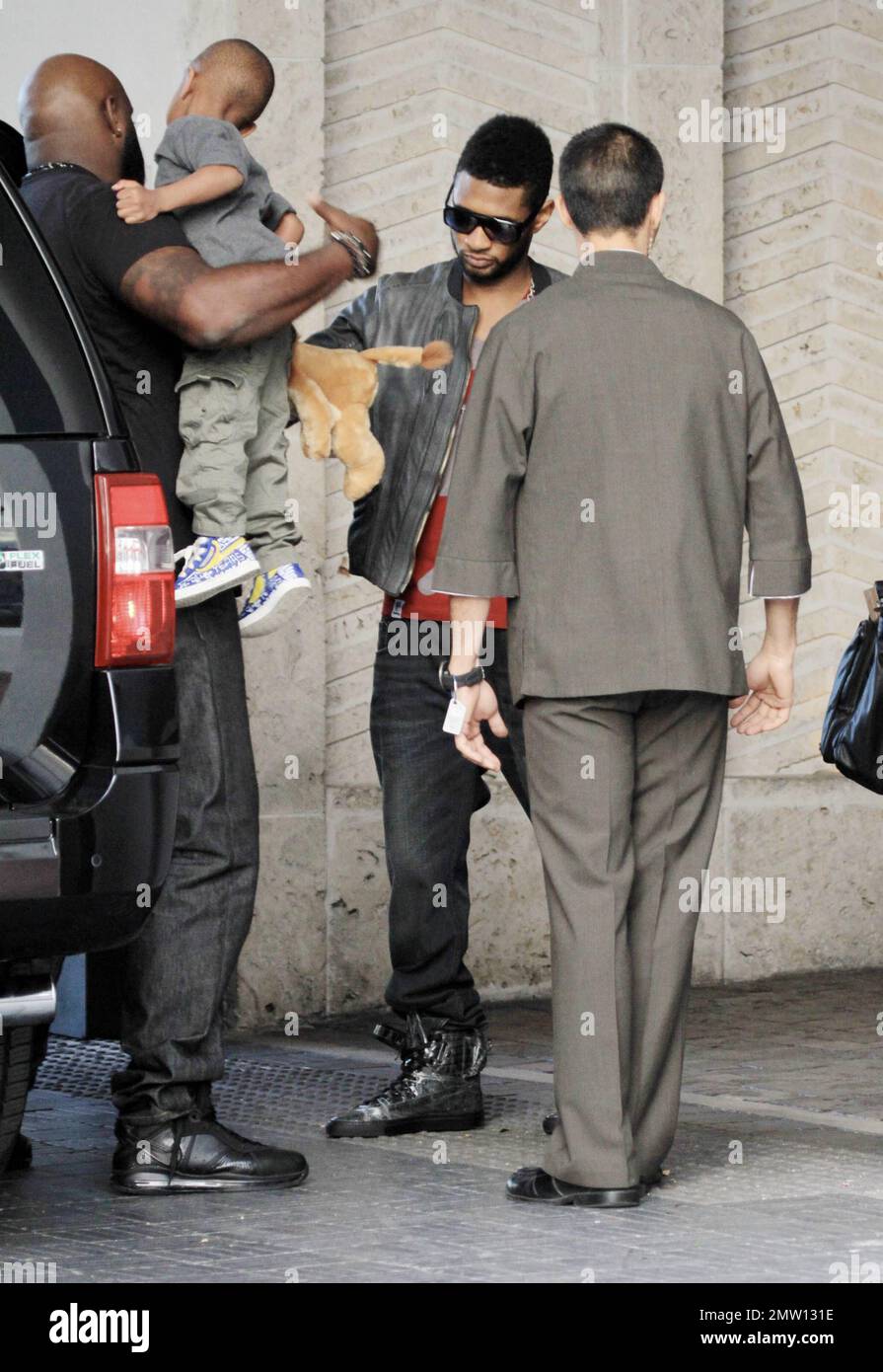 Rapper Usher and his children with the help of bodyguards and staff ...