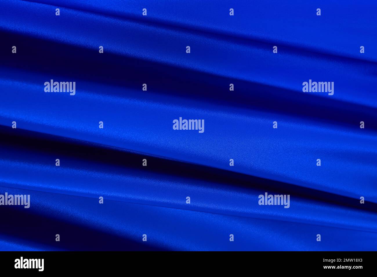 The texture of a luxurious smooth fabric in blue with folds and waves ...