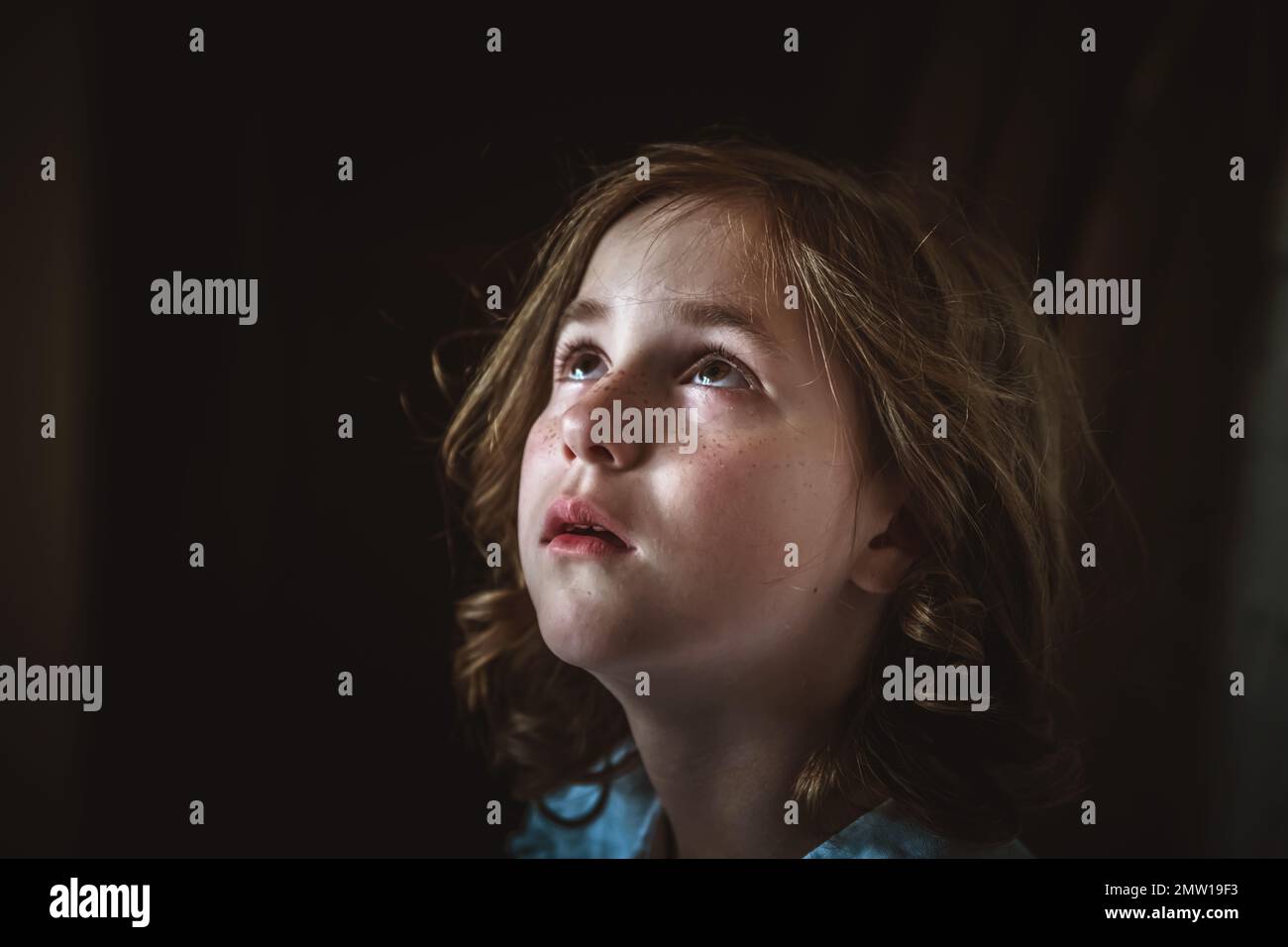 a little girl sits alone in a dark hallway. fear, loneliness Stock ...