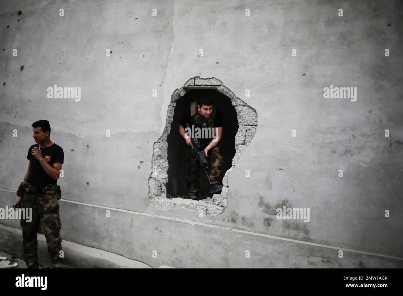 A soldier with the Iraqi special forces looks through the hole of a ...