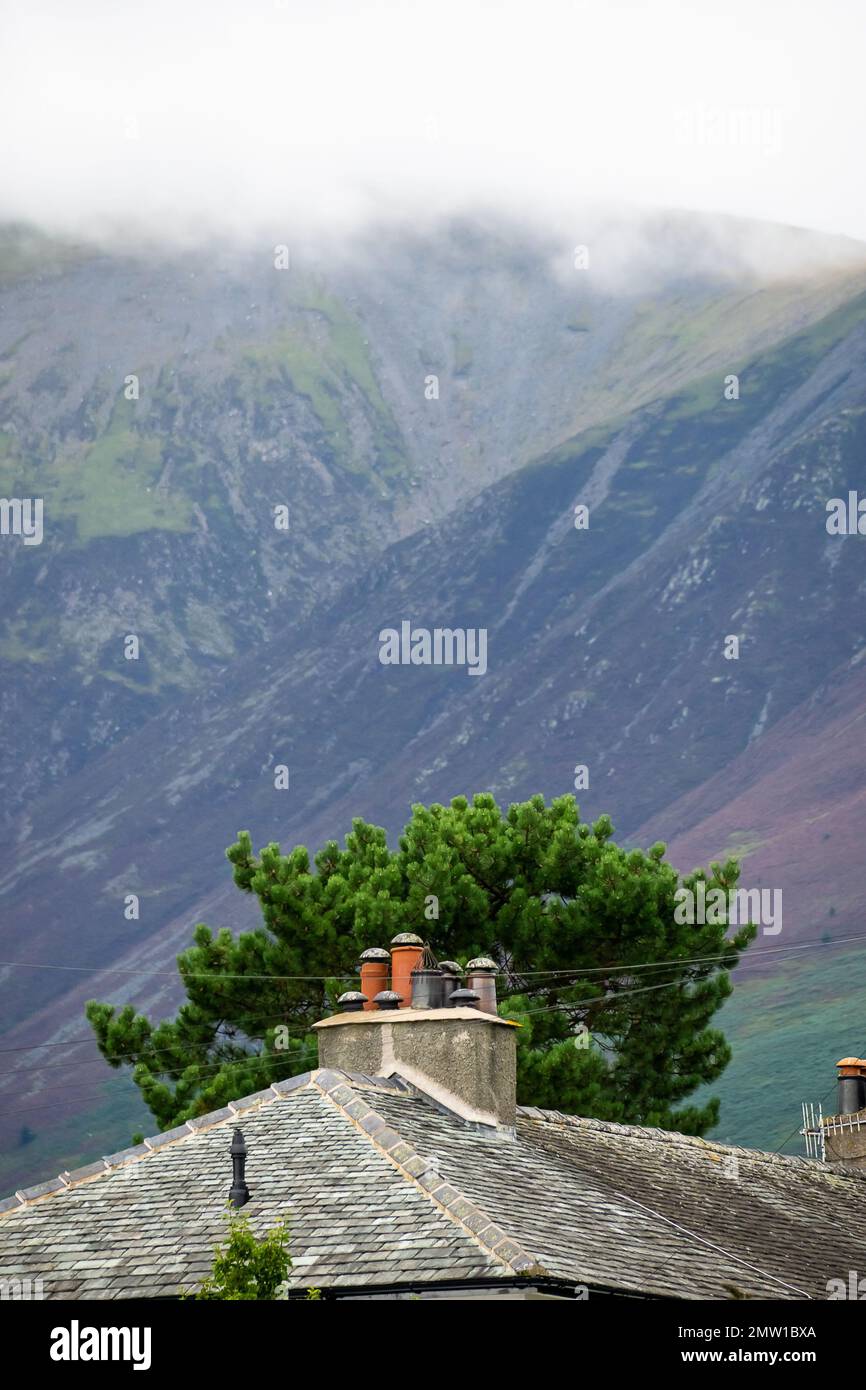 A vertical shot of a rustic stone building with rugged mountain ranges ...