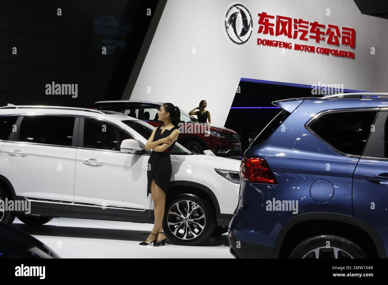 Female staff members stand near vehicles from Chinese automaker ...