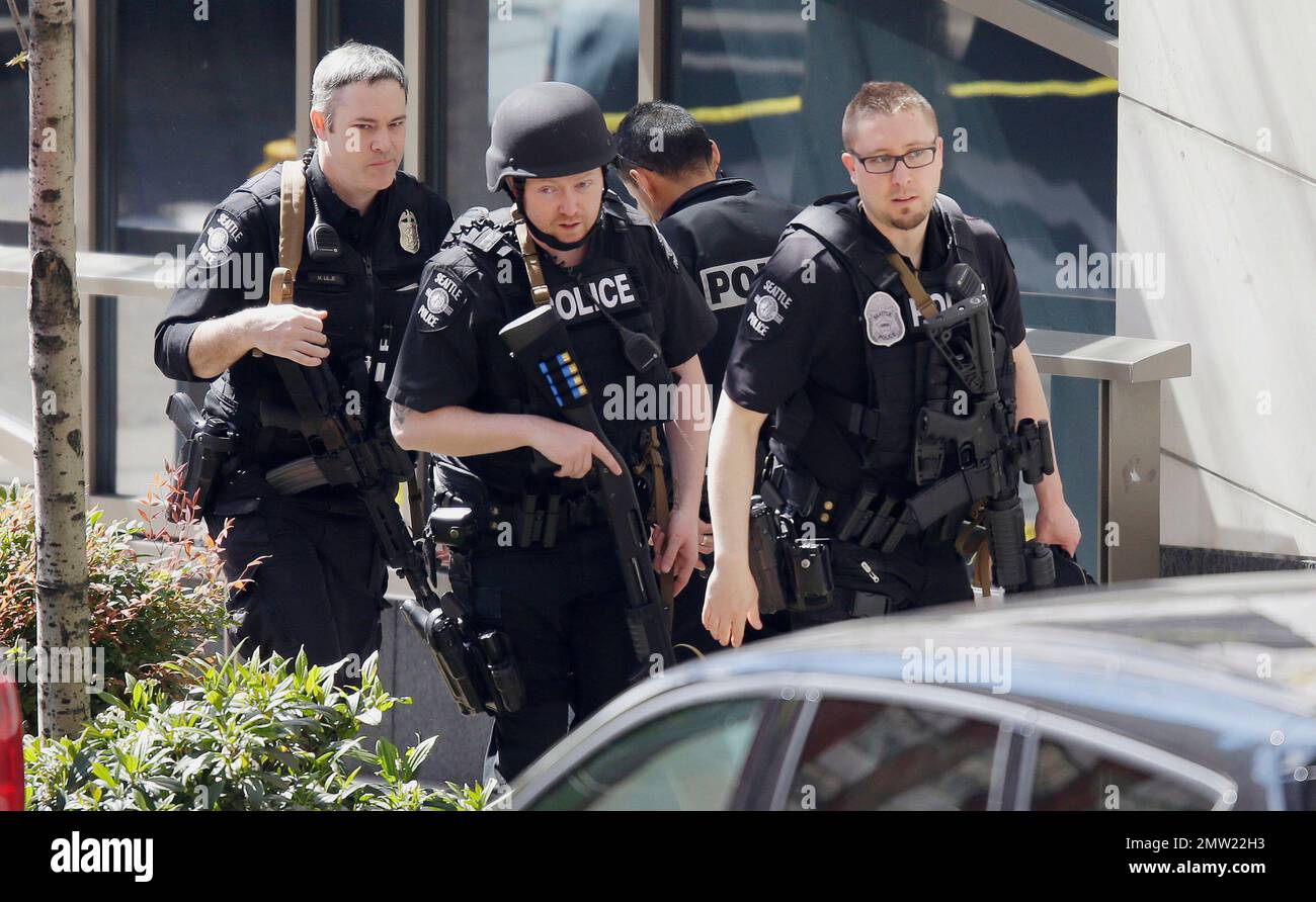 Seattle Police officers walk with guns near the scene of a shooting ...