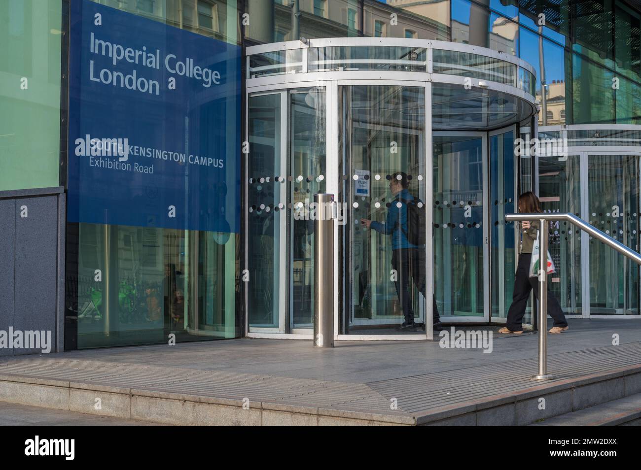 Young man and woman entering through revolving door to Imperial College ...
