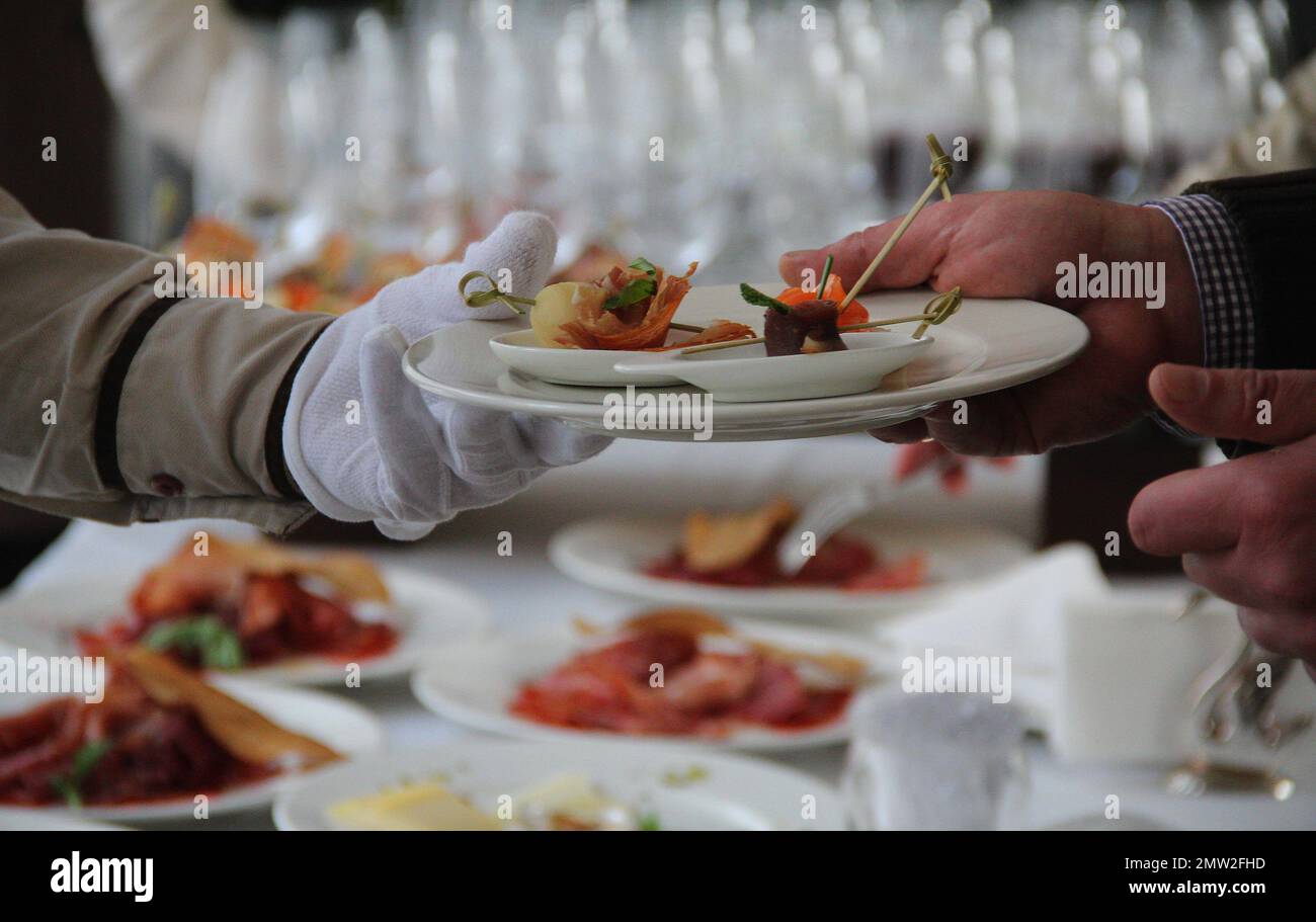 The waiter puts appetizers on the man's plate during the buffet table ...