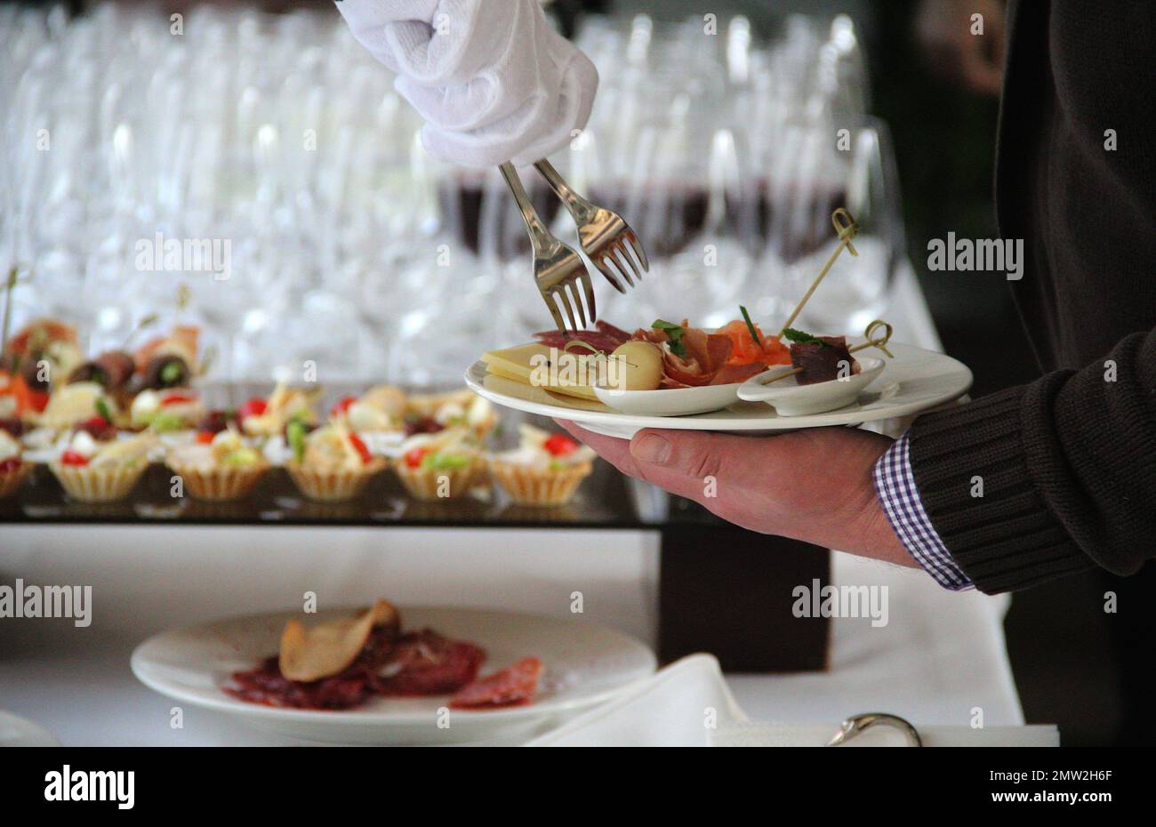 Waiter passing a plate of appetizers to a man at a banquet Stock Photo ...