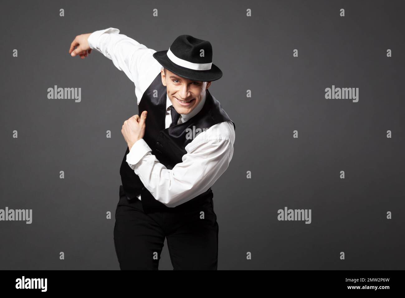 Confident young man dancing in gangster style suite. Studio shot ...