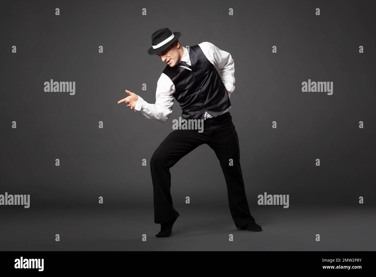 Confident young man dancing in gangster style suite. Studio shot ...