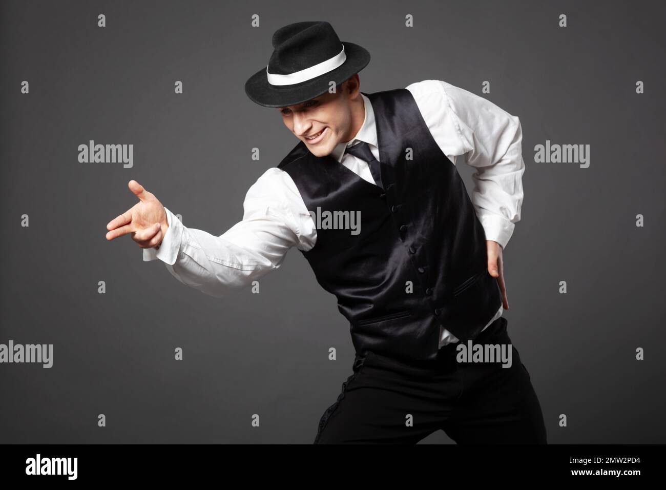 Confident young man dancing in gangster style suite. Studio shot ...