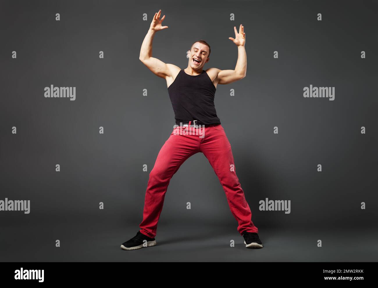 Full body portrait of young man dancing against gray background. Low ...