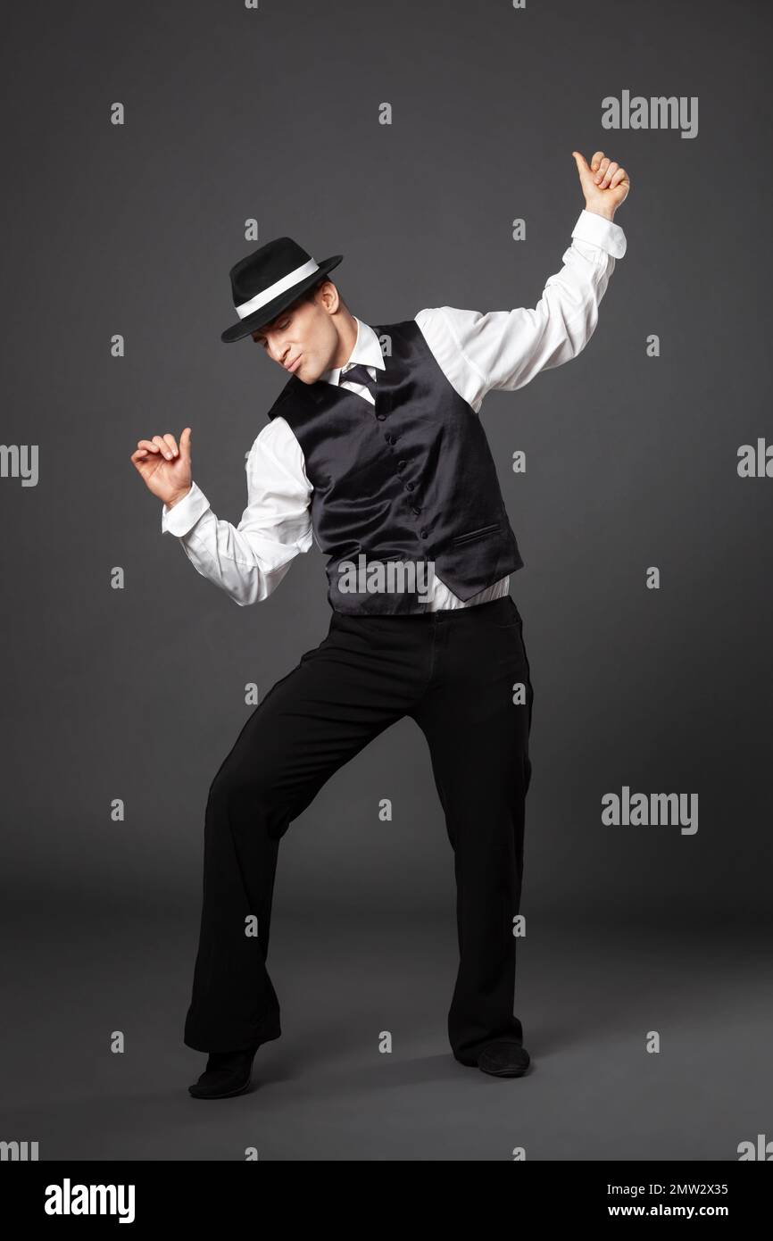 Confident young man dancing in gangster style suite. Studio shot ...