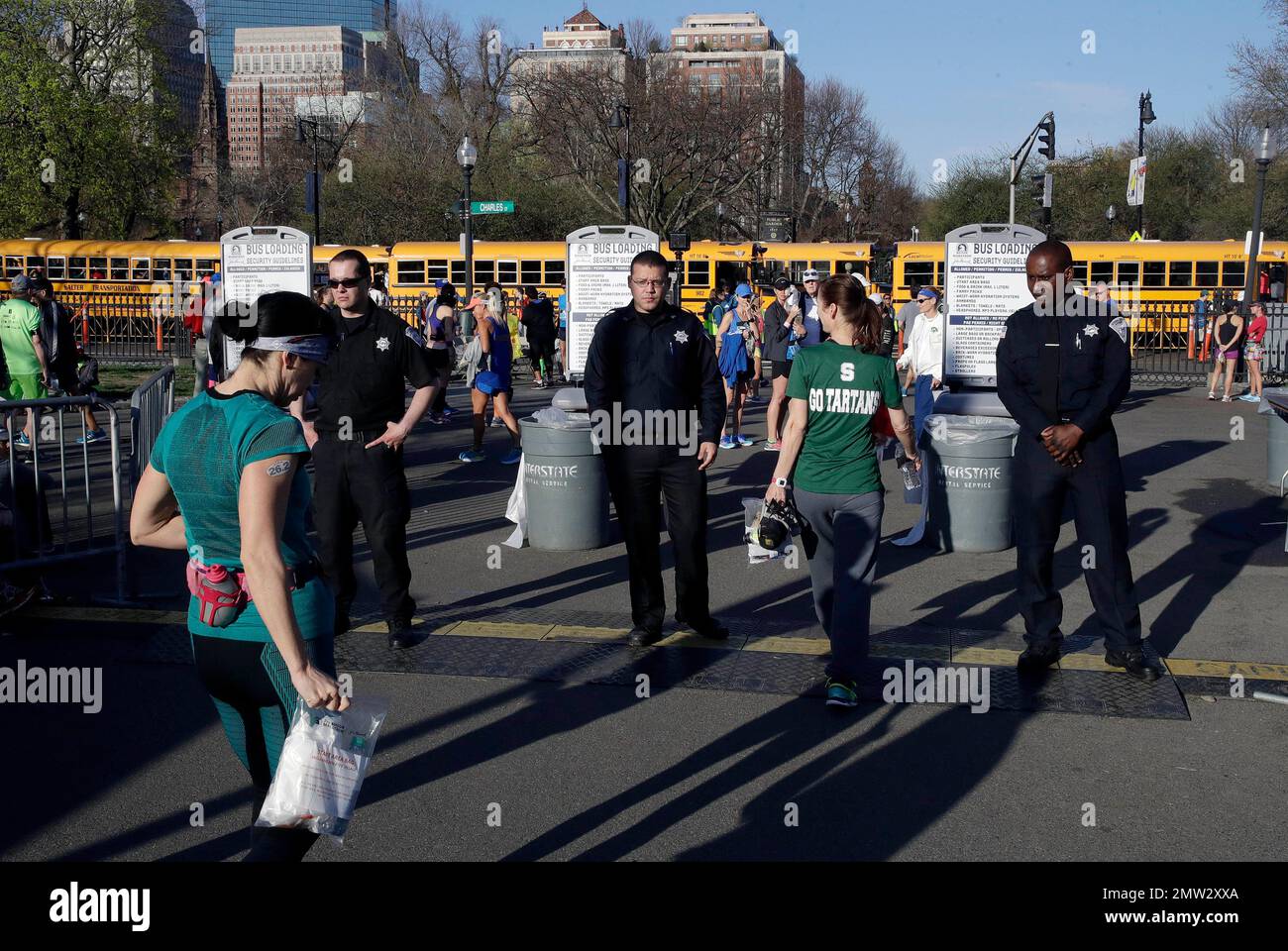 Runners pass through a security check in Boston to board buses for the ...