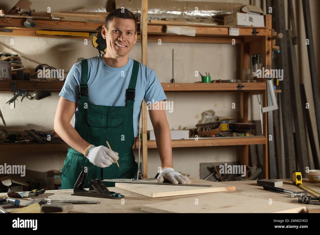 Professional carpenter measuring wooden board in workshop Stock Photo ...