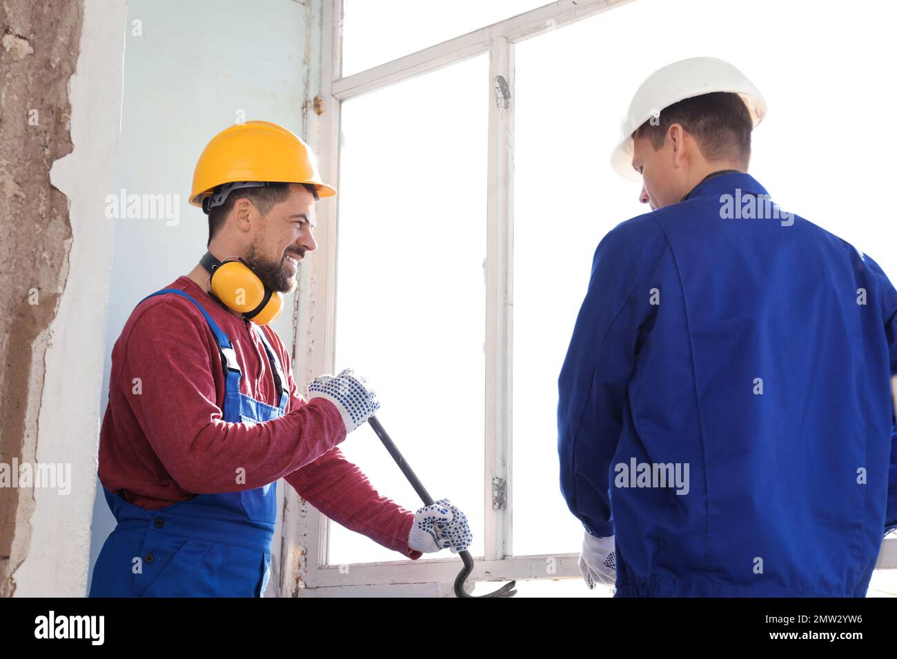 Workers dismantling old window with crowbar indoors Stock Photo - Alamy