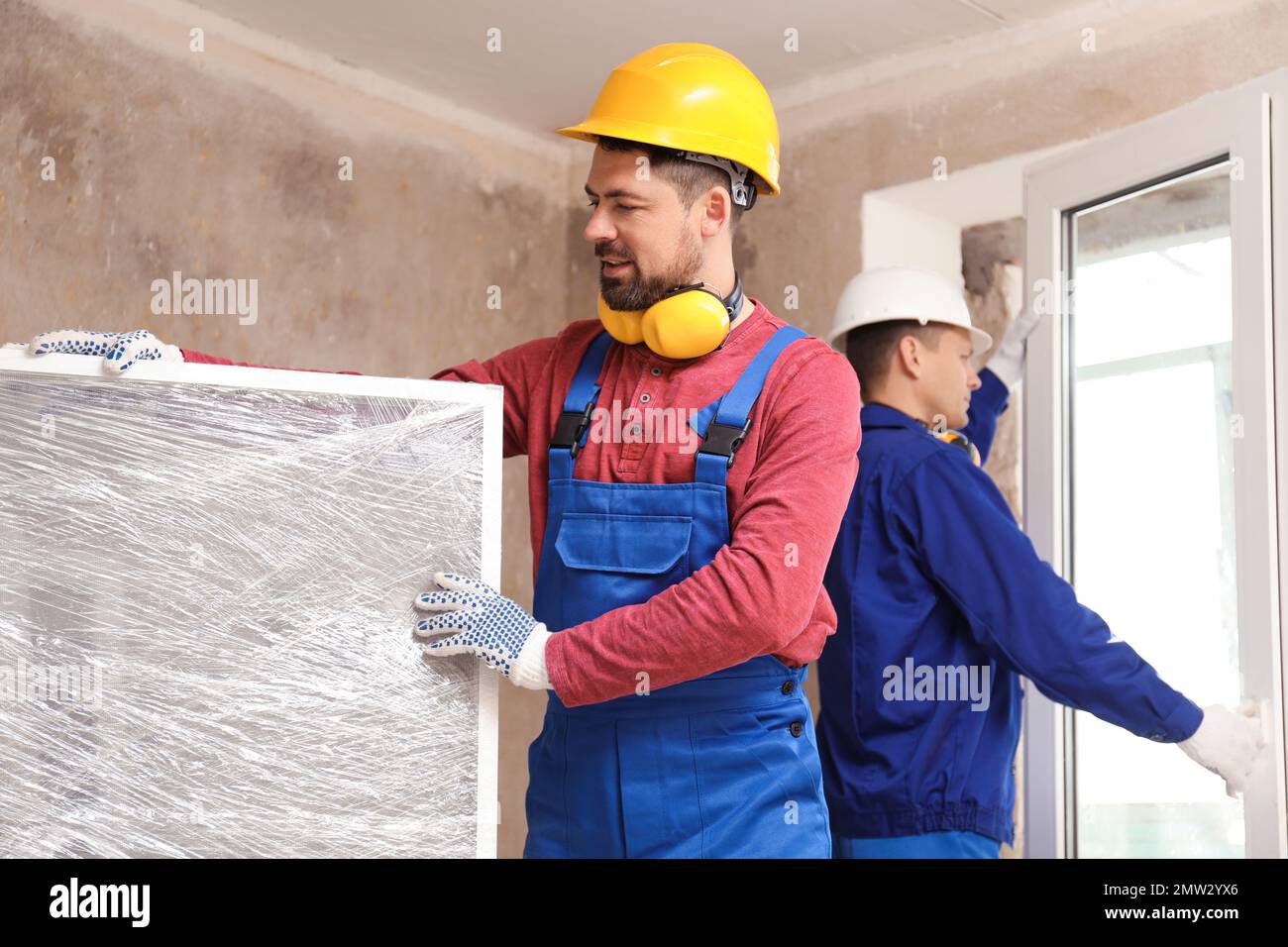 Workers in uniform installing plastic windows indoors Stock Photo - Alamy