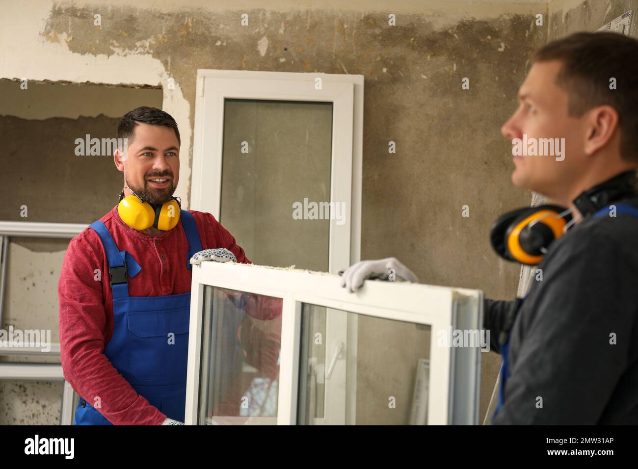 Workers in uniform with new plastic window indoors Stock Photo - Alamy