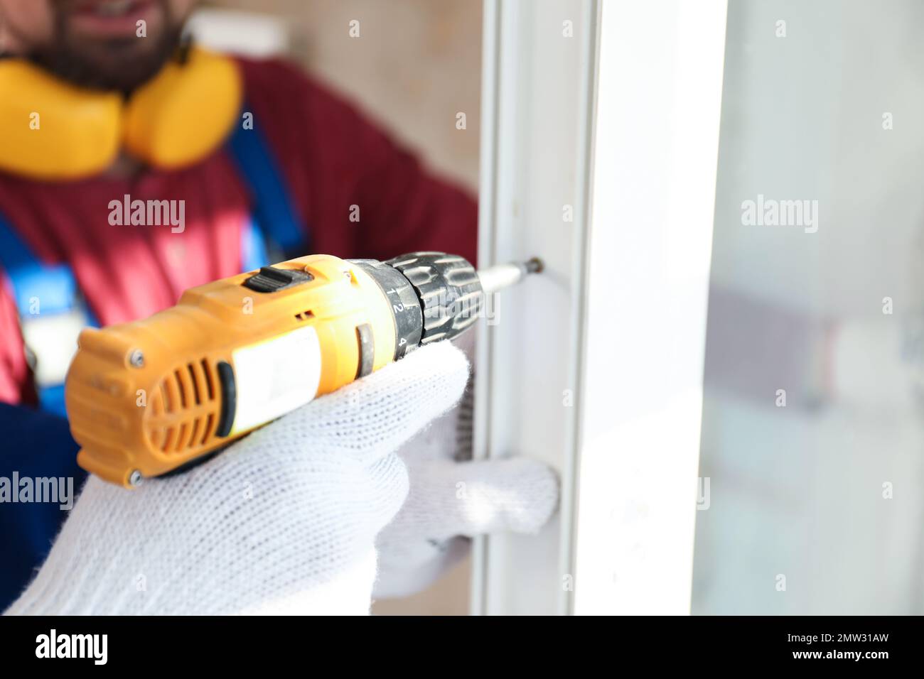 Workers using electric screwdriver for window installation indoors ...