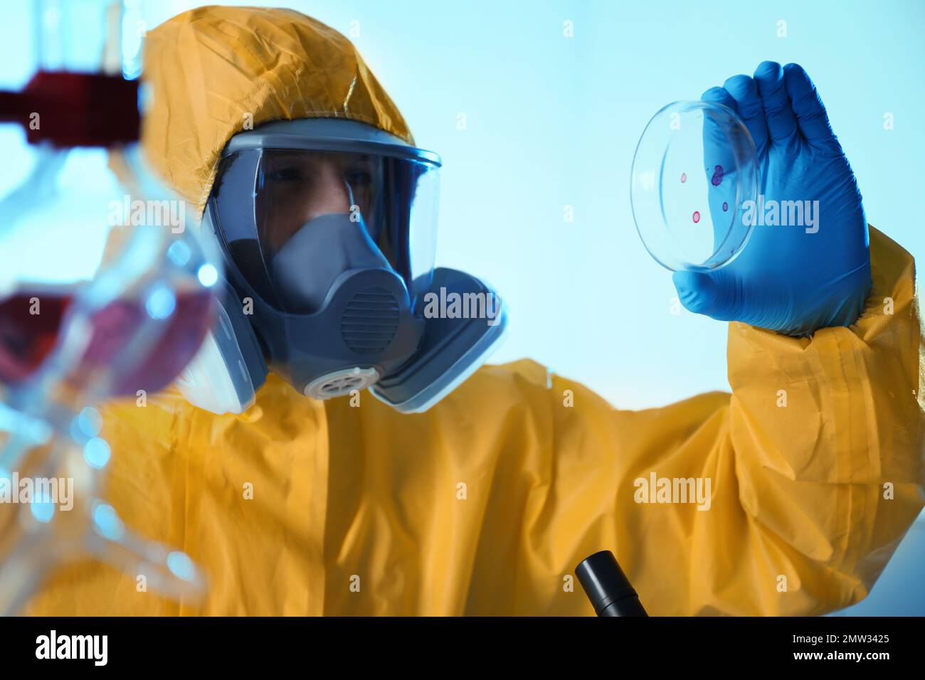 Scientist in chemical protective suit with Petri dish at laboratory ...