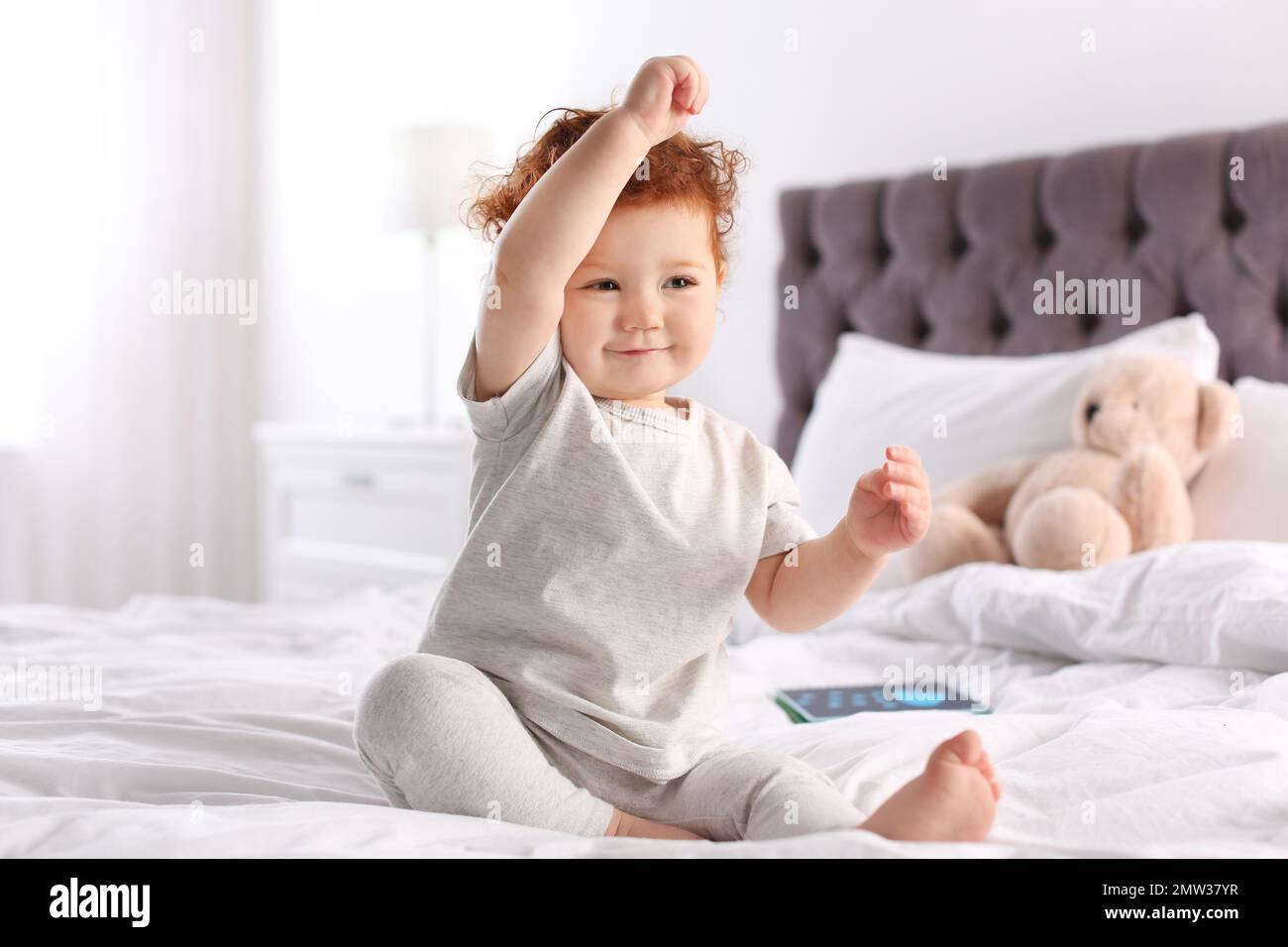 Cute little child sitting on bed at home Stock Photo - Alamy