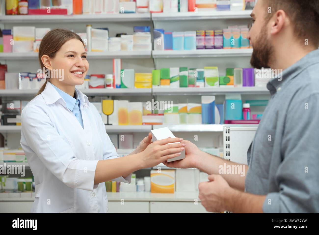 Professional pharmacist giving medicine to customer in modern drugstore ...