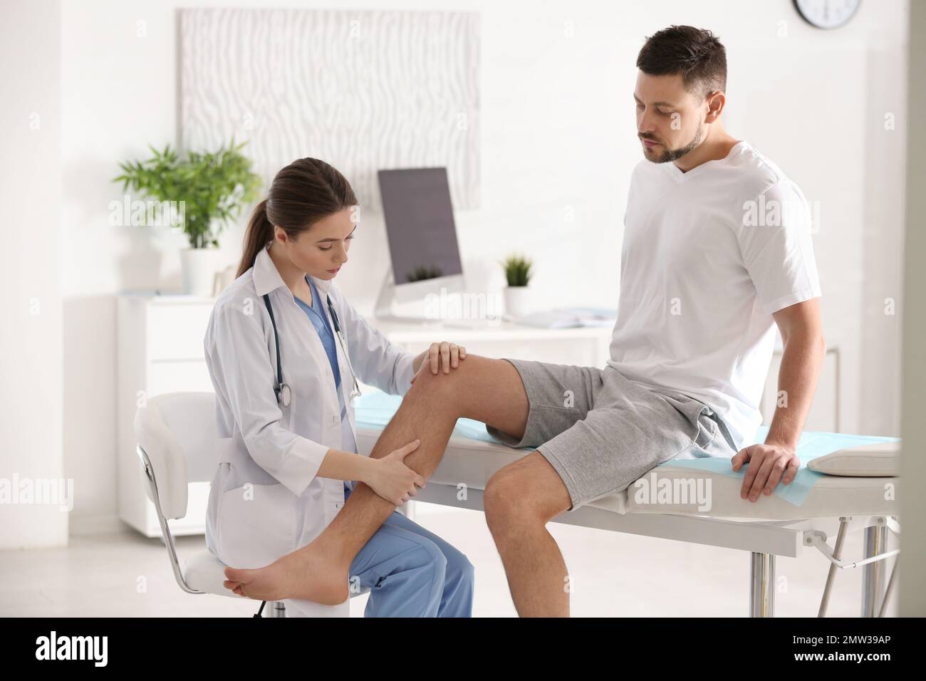 Female orthopedist examining patient's leg in clinic Stock Photo - Alamy
