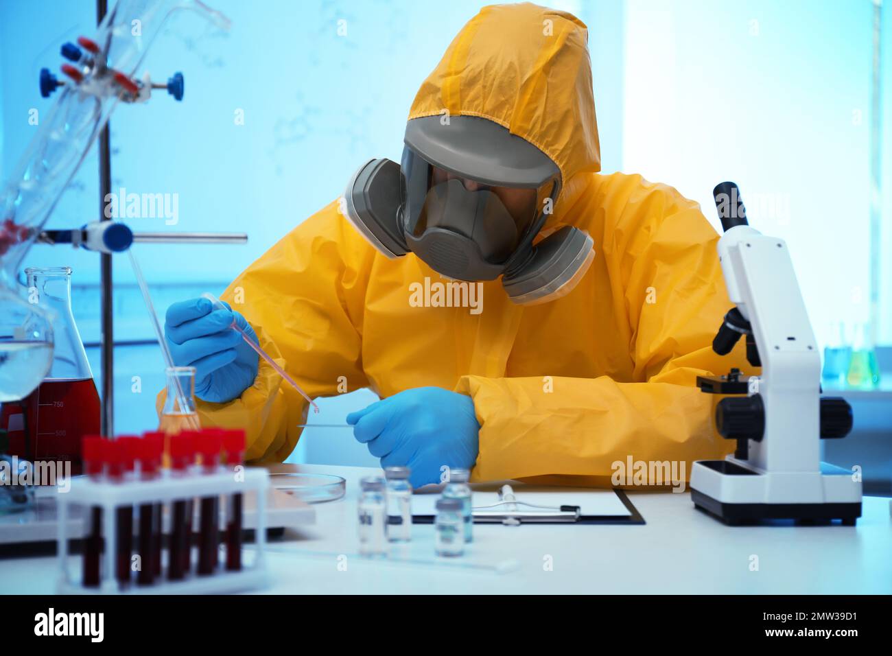 Scientist in chemical protective suit dripping reagent on microscope ...
