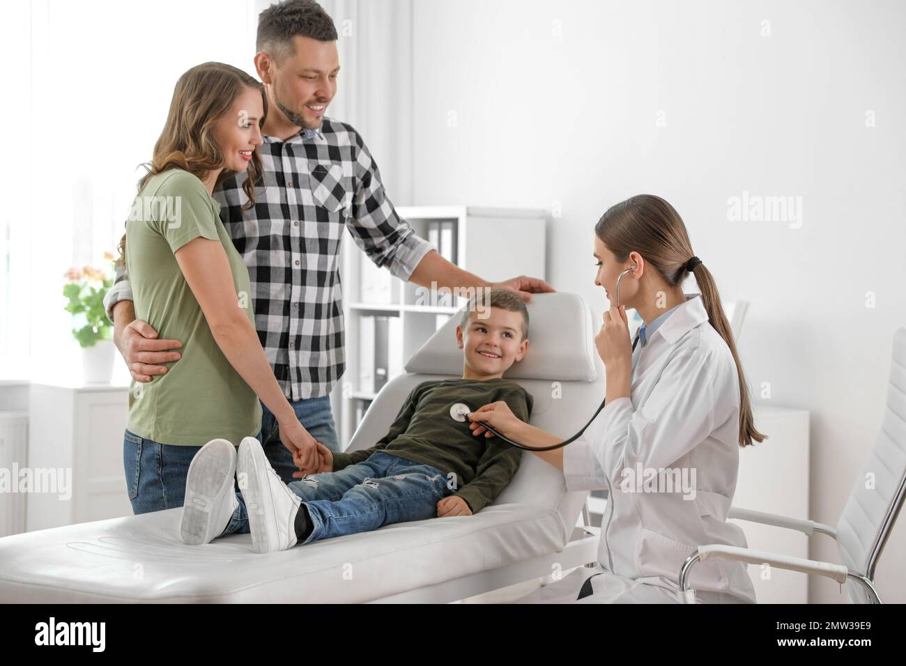 Parents and son visiting pediatrician. Doctor examining little patient ...
