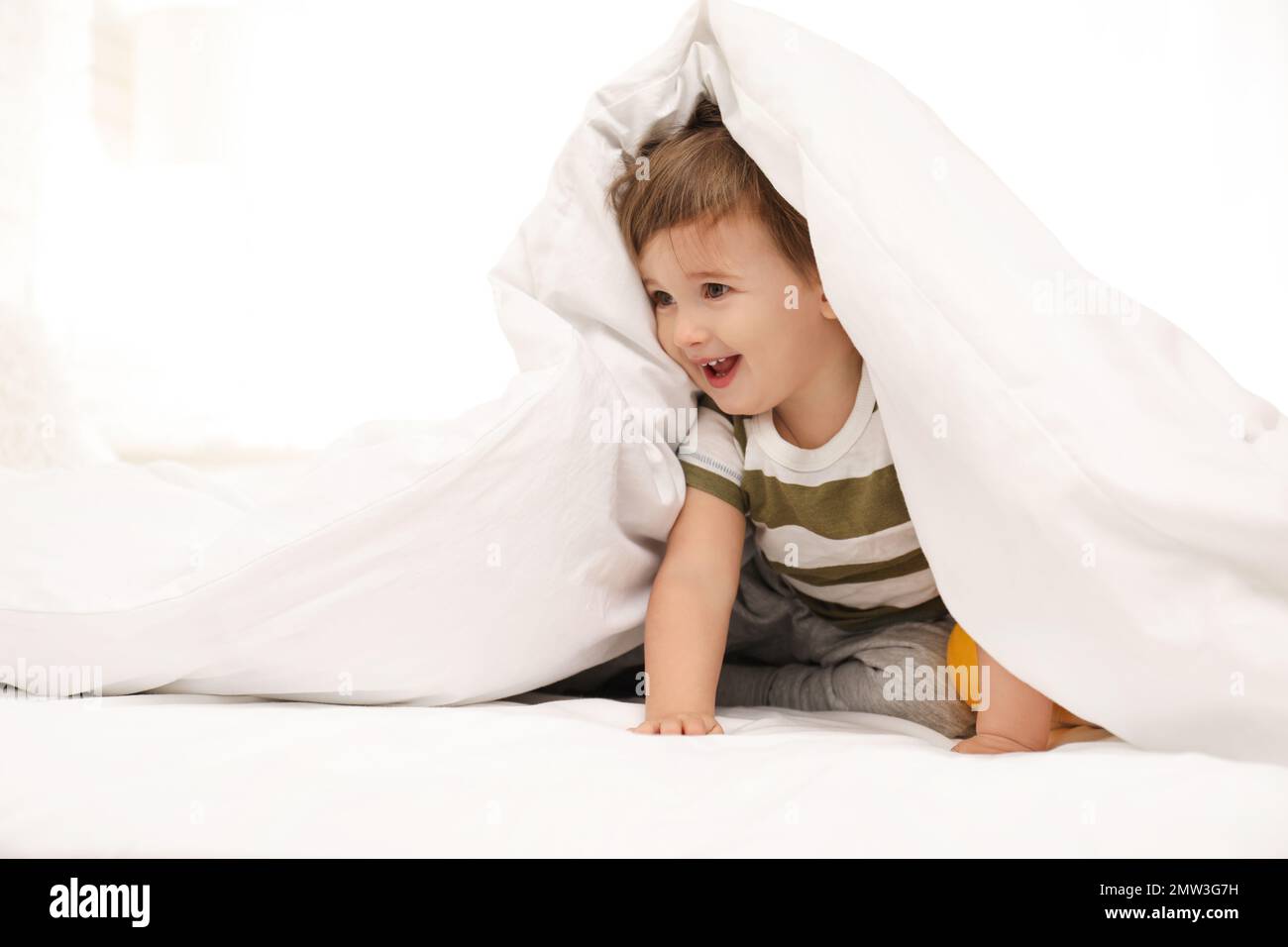 Cute little child playing under blanket in bed Stock Photo - Alamy