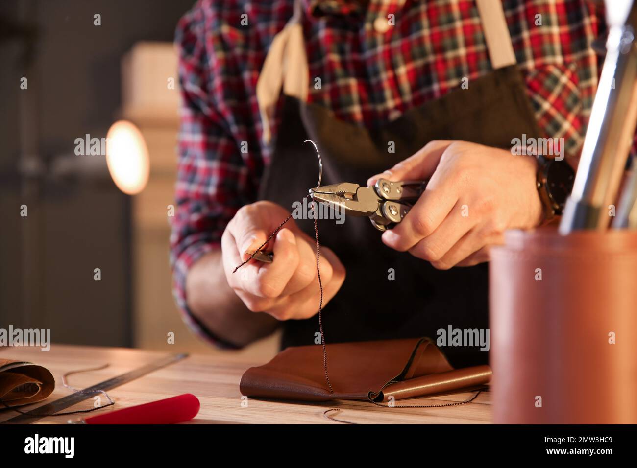 Man threading needle for leather working, closeup Stock Photo - Alamy