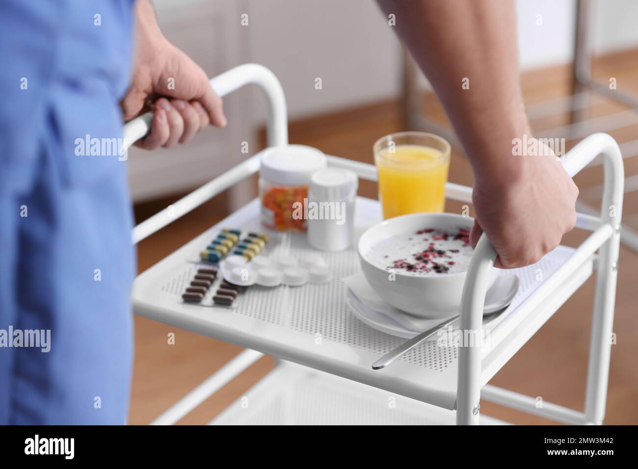 Nurse bringing patient's food and medicine on serving trolley, closeup ...