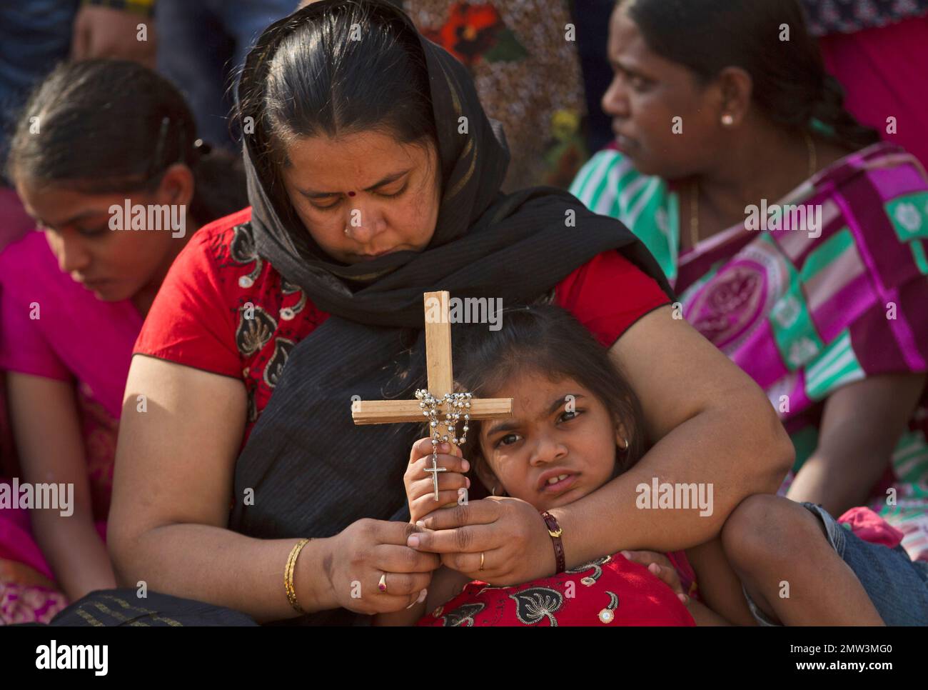 An Indian mother and daughter pray as they watch the reenacting of the ...