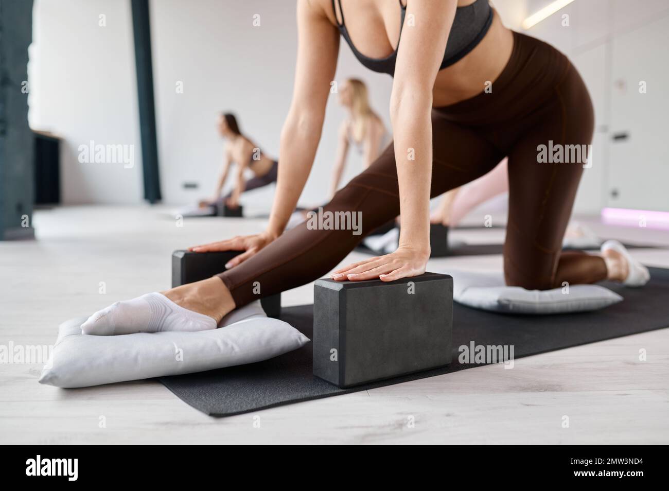 Closeup woman practicing yoga using fitness block for leg-split ...