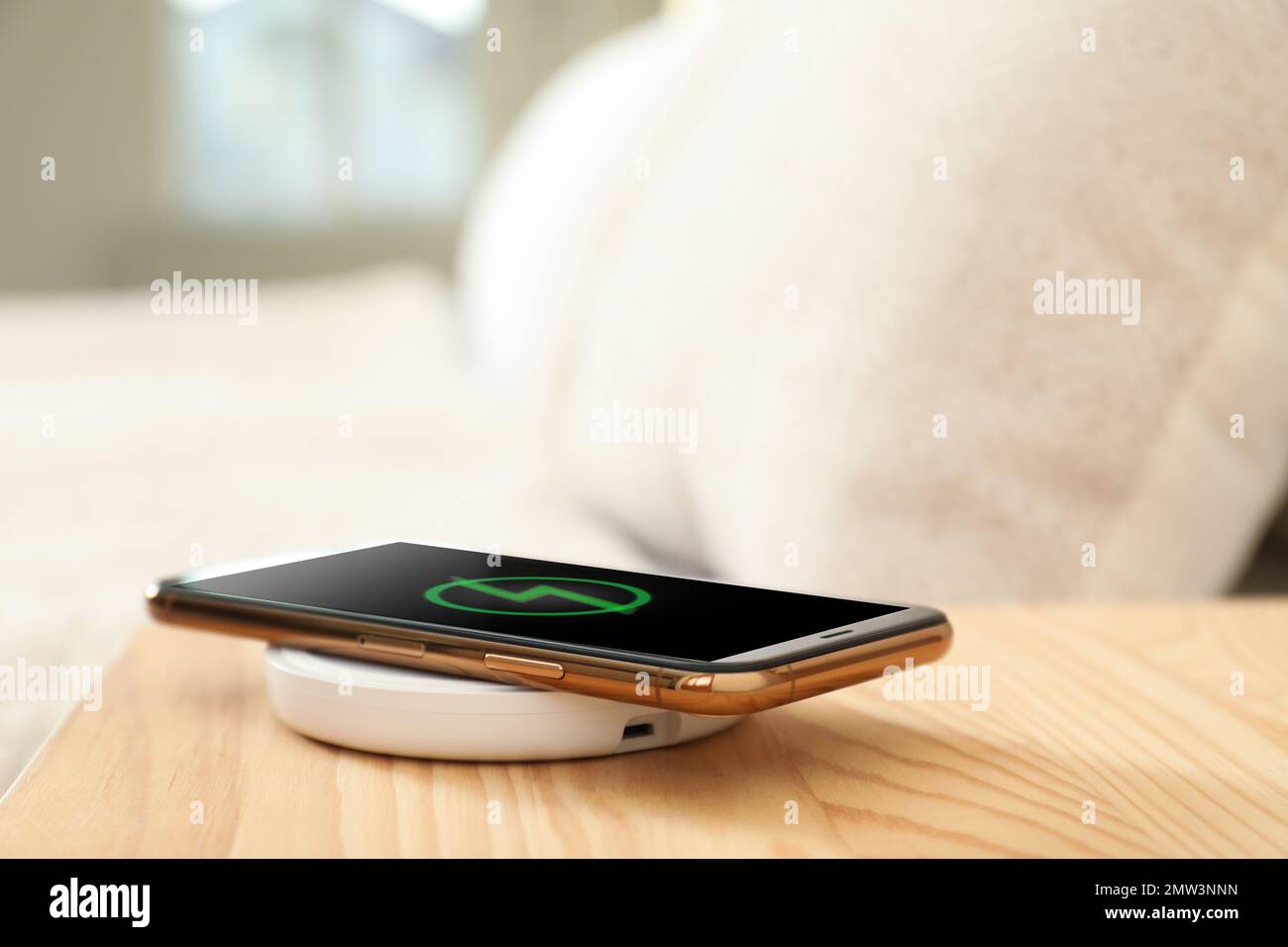 Modern mobile phone charging on wireless pad in bedroom, closeup Stock ...