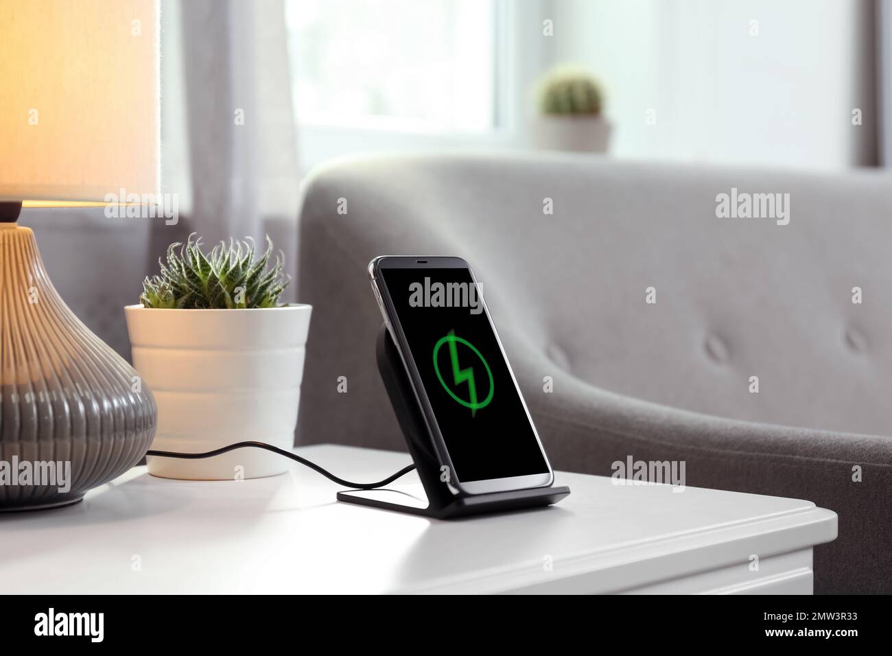 Smartphone charging on wireless pad in room Stock Photo - Alamy