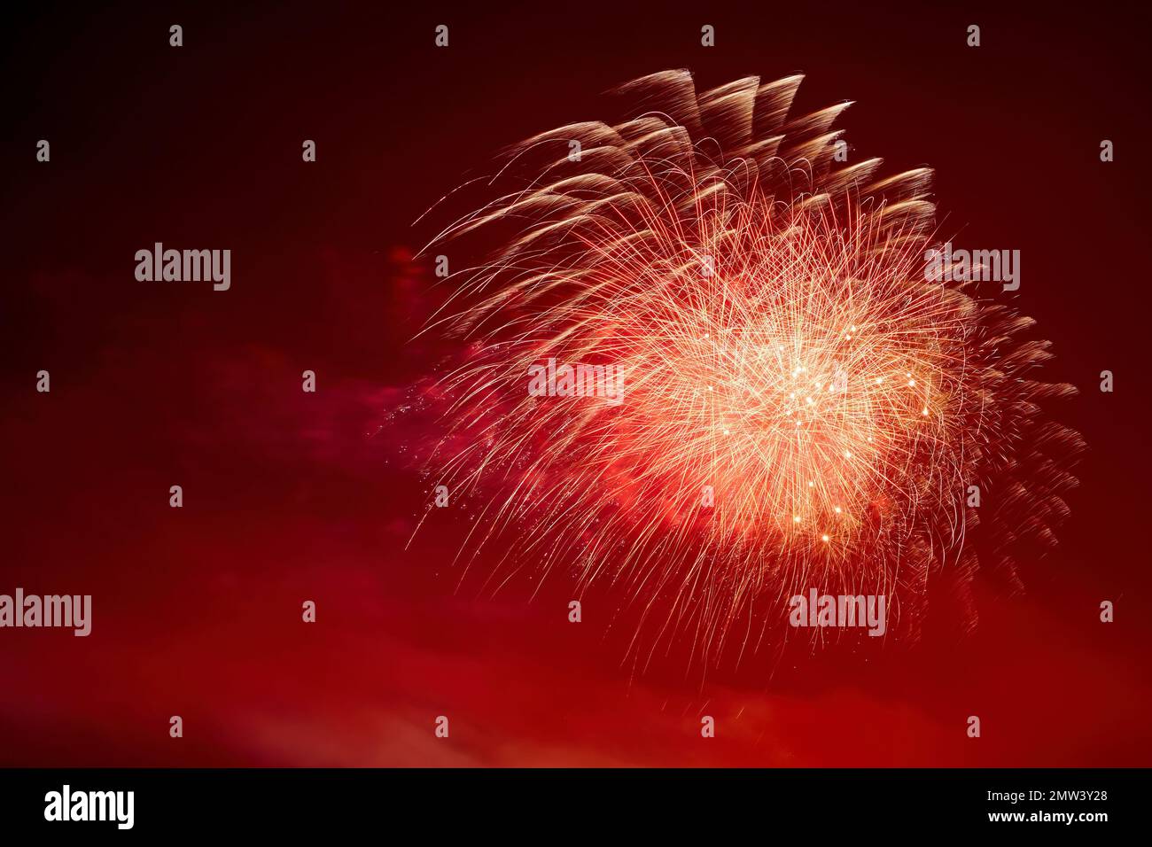 A low angle motion blur of a red firework illuminating the sky with a ...