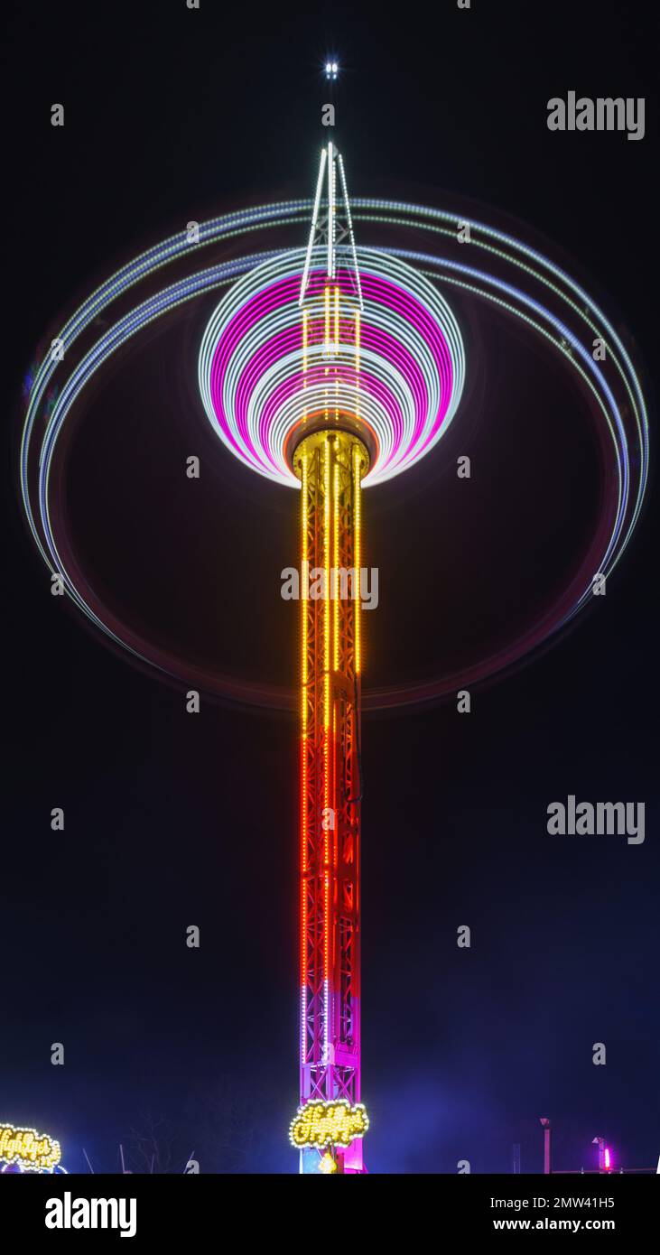 A Blue rotating funfair ride at night, light trails, long exposure ...