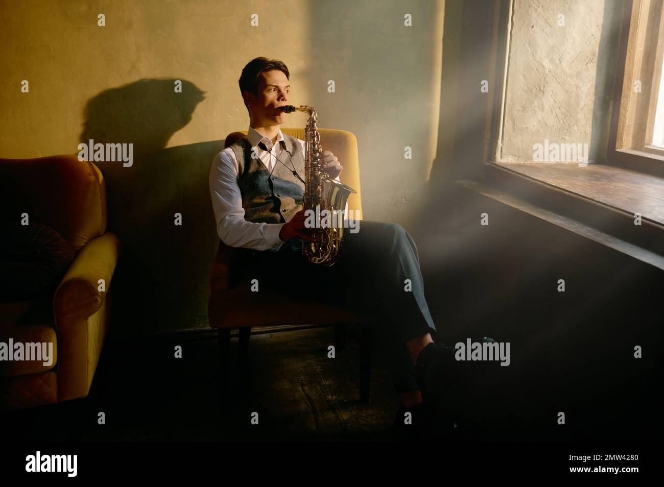 Jazz musician playing saxophone front of window Stock Photo - Alamy