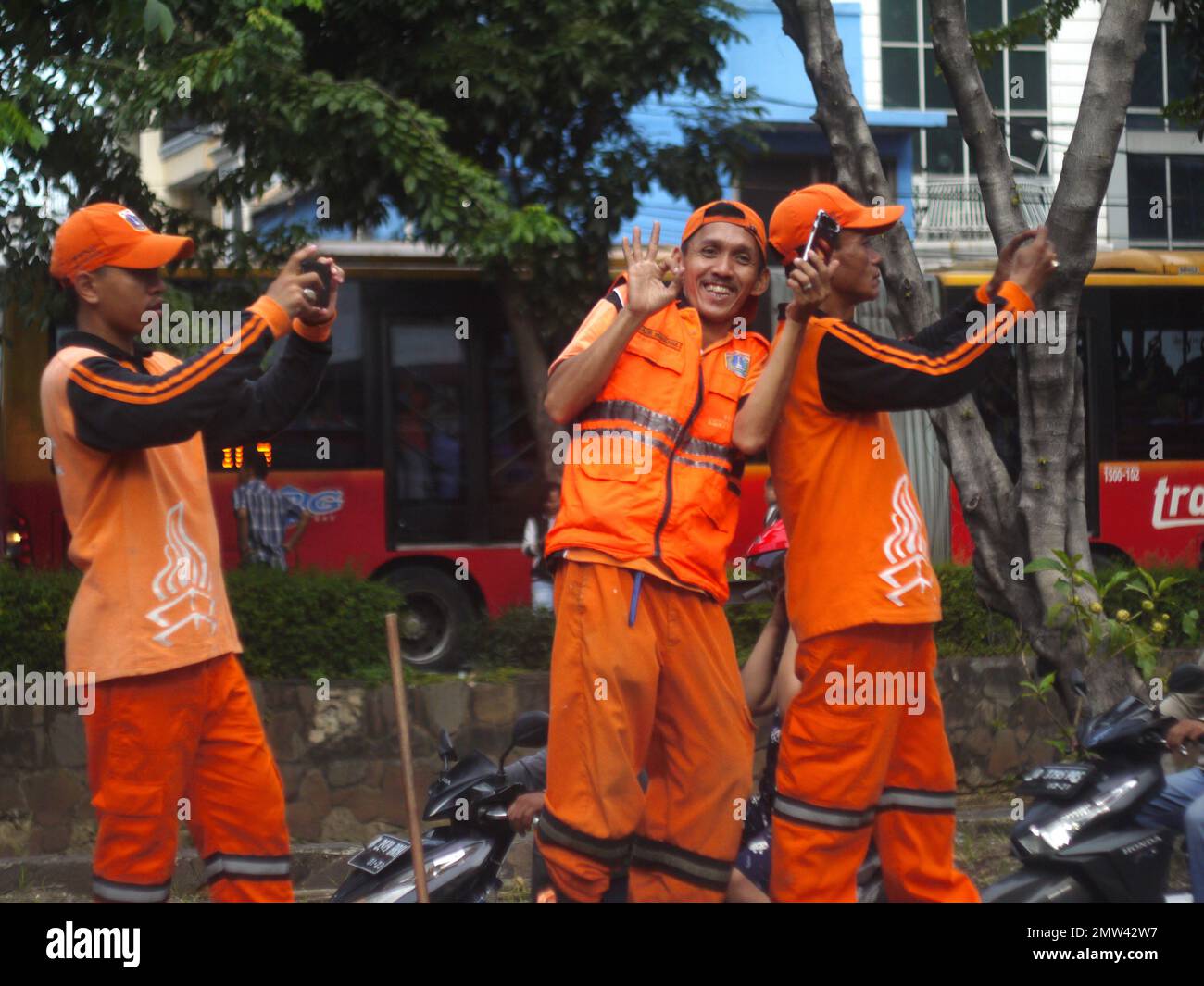 portrait of three men wearing orange shirts and hats. the two people ...