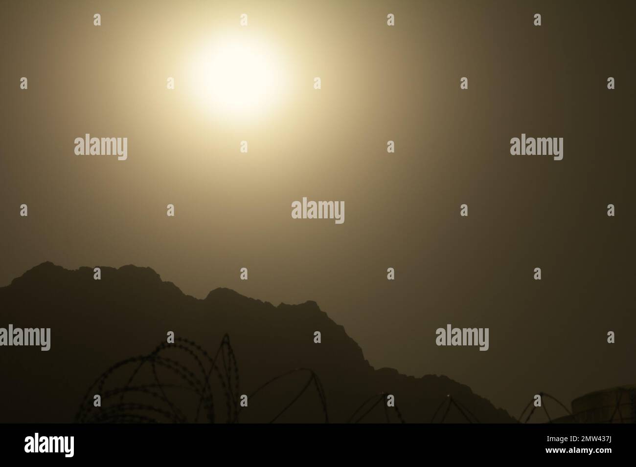 A night photograph showing the view over barbed wire under a full moon ...