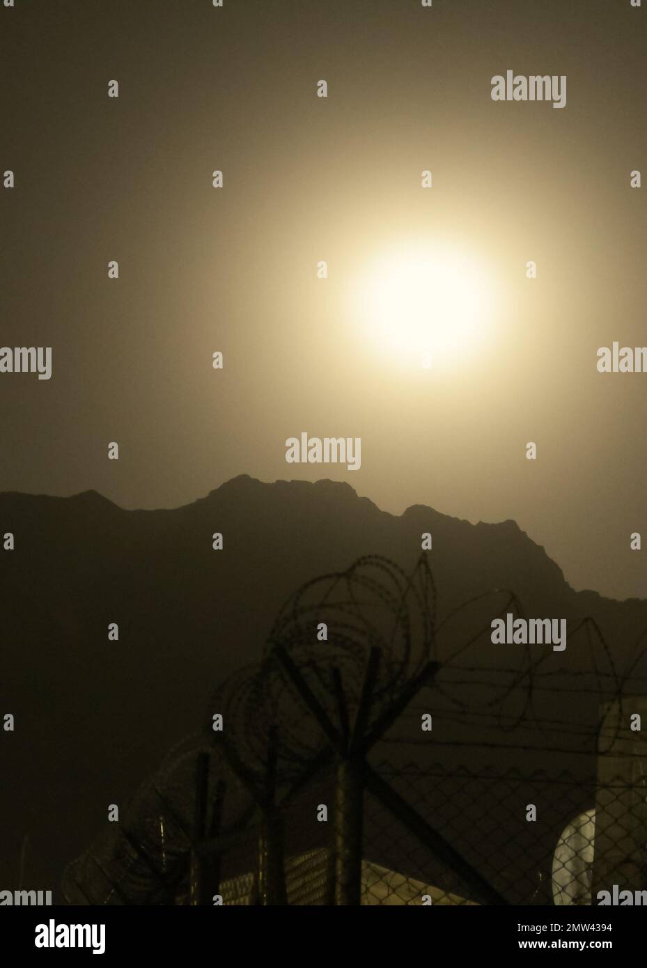 A night photograph showing the view over barbed wire under a full moon ...