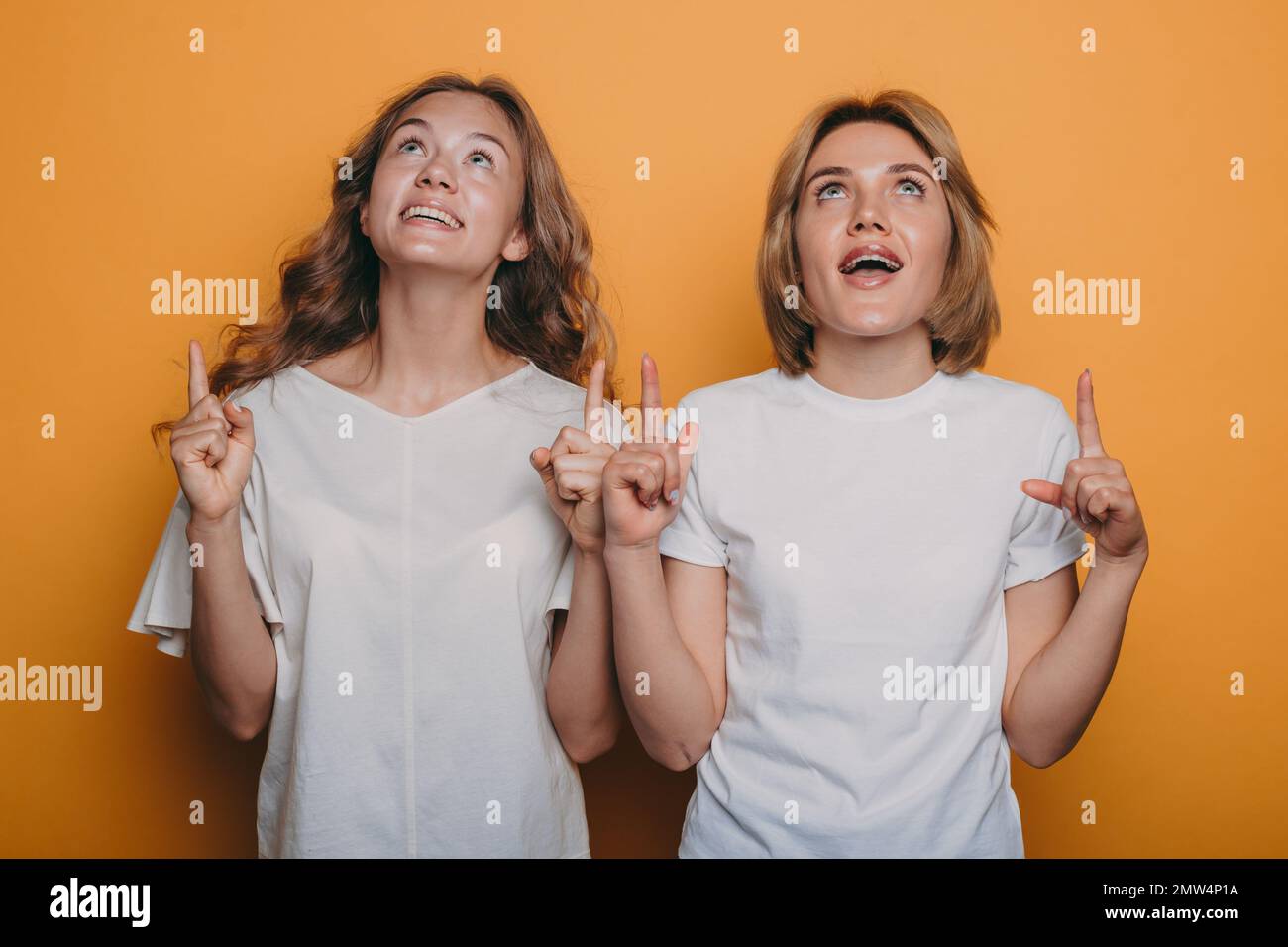 Happy screaming young women pointing and looking up with open mouths ...