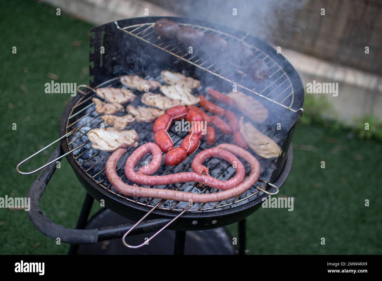 A typical Spanish bacon and chorizo barbecue being cooked on a grill ...