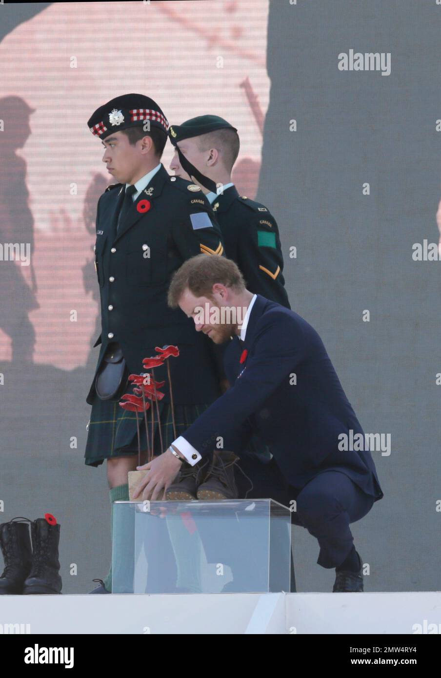 Britain's Prince Harry prepares to place poppies next to a pair of ...